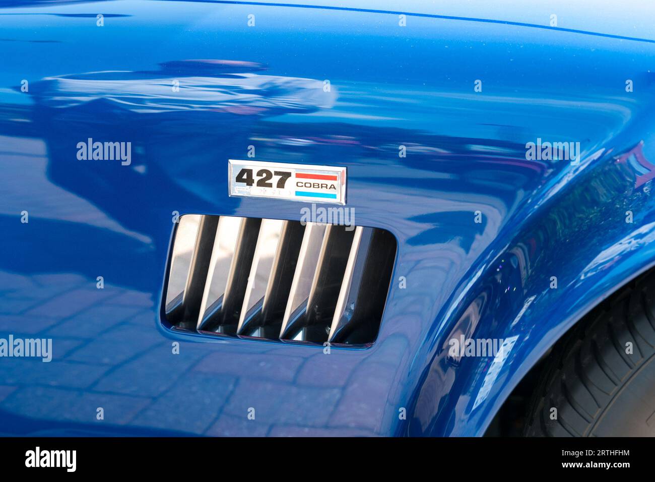A close-up of a bright blue AC Cobra car with an emblem in Manchester ...