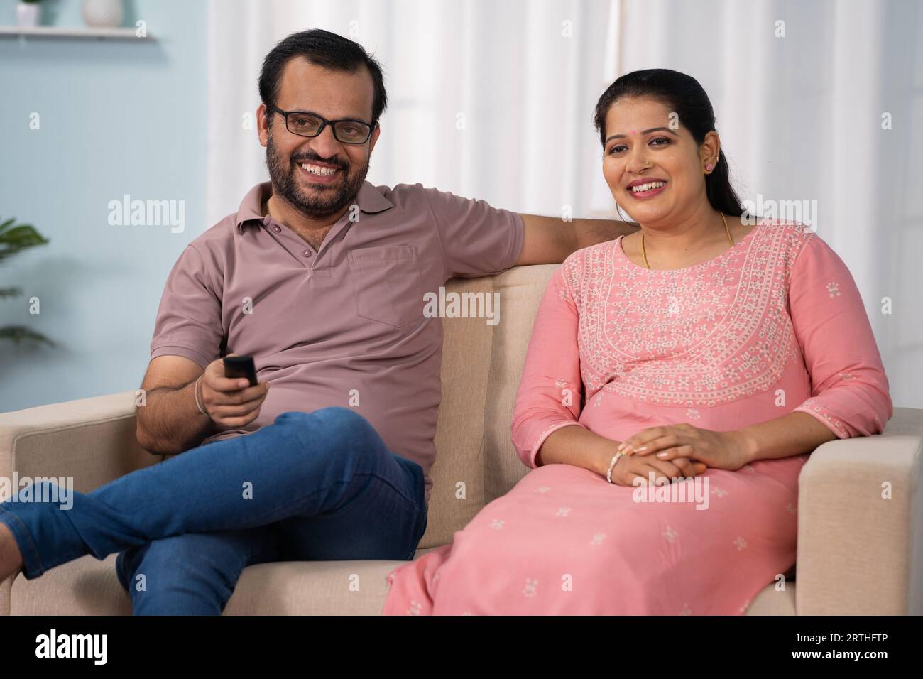 Happy relaxed indian middle aged couple watching TV or television by ...