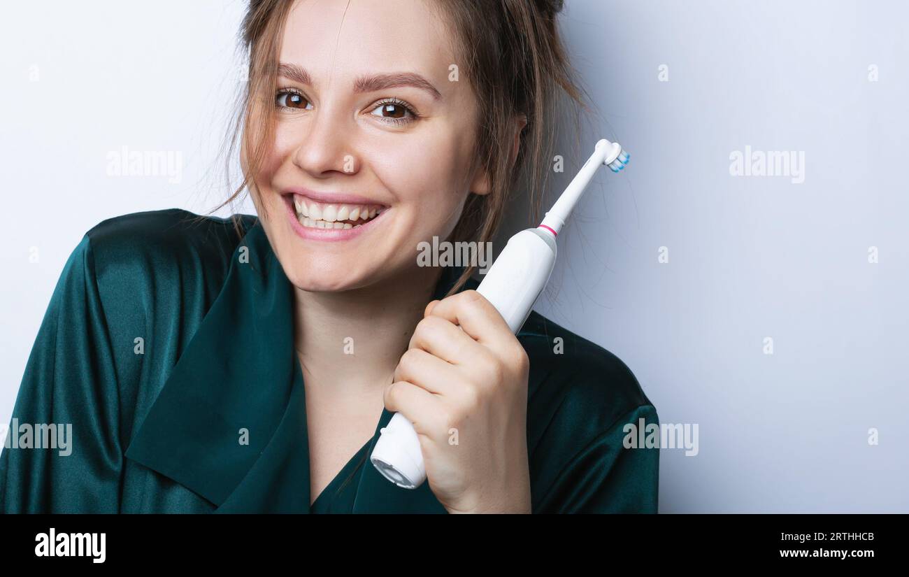 Happy woman with an electric toothbrush Stock Photo - Alamy