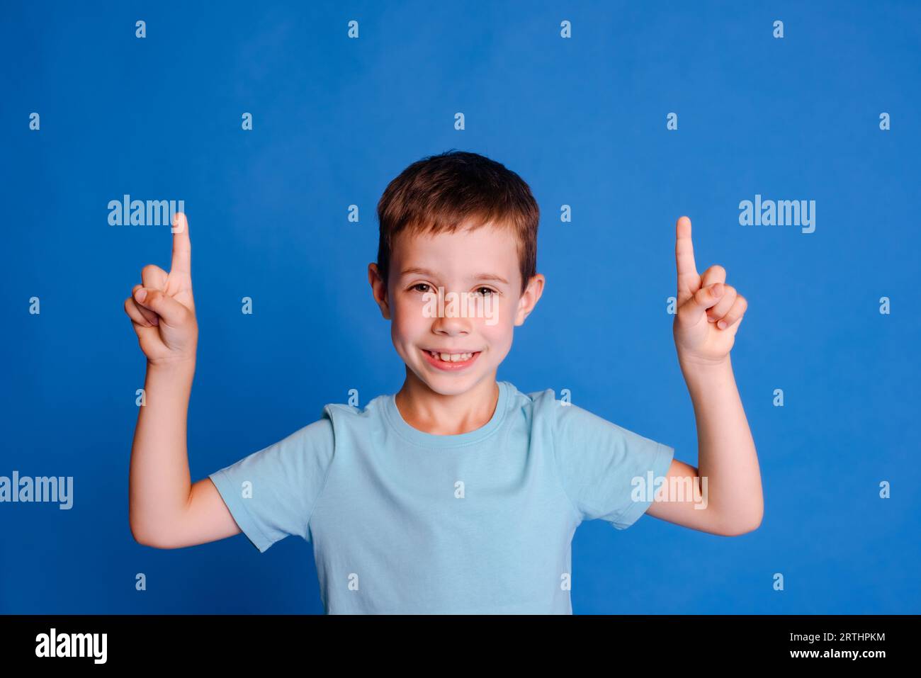 headshot schoolboy point index fingers up to free copy space on light ...