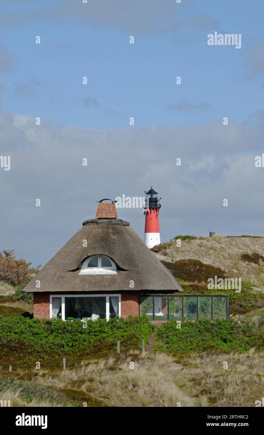 Thatched roof house in front of the lighthouse Stock Photo - Alamy