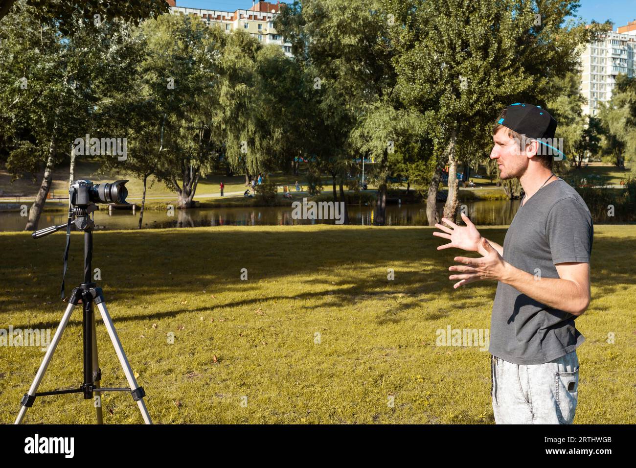 Young man, digital vlogging blogger in the park, confident young guy ...