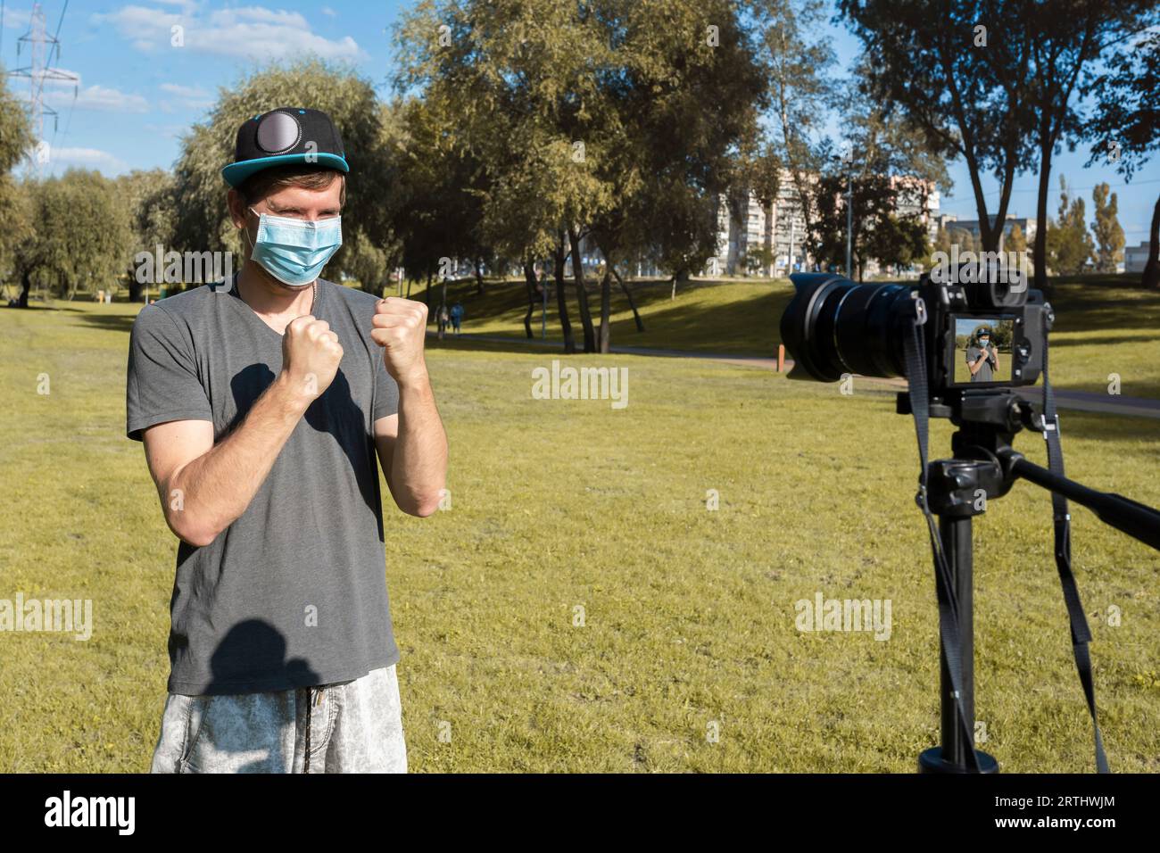 Young hipster blogger, wearing a protective medical mask, recording a ...