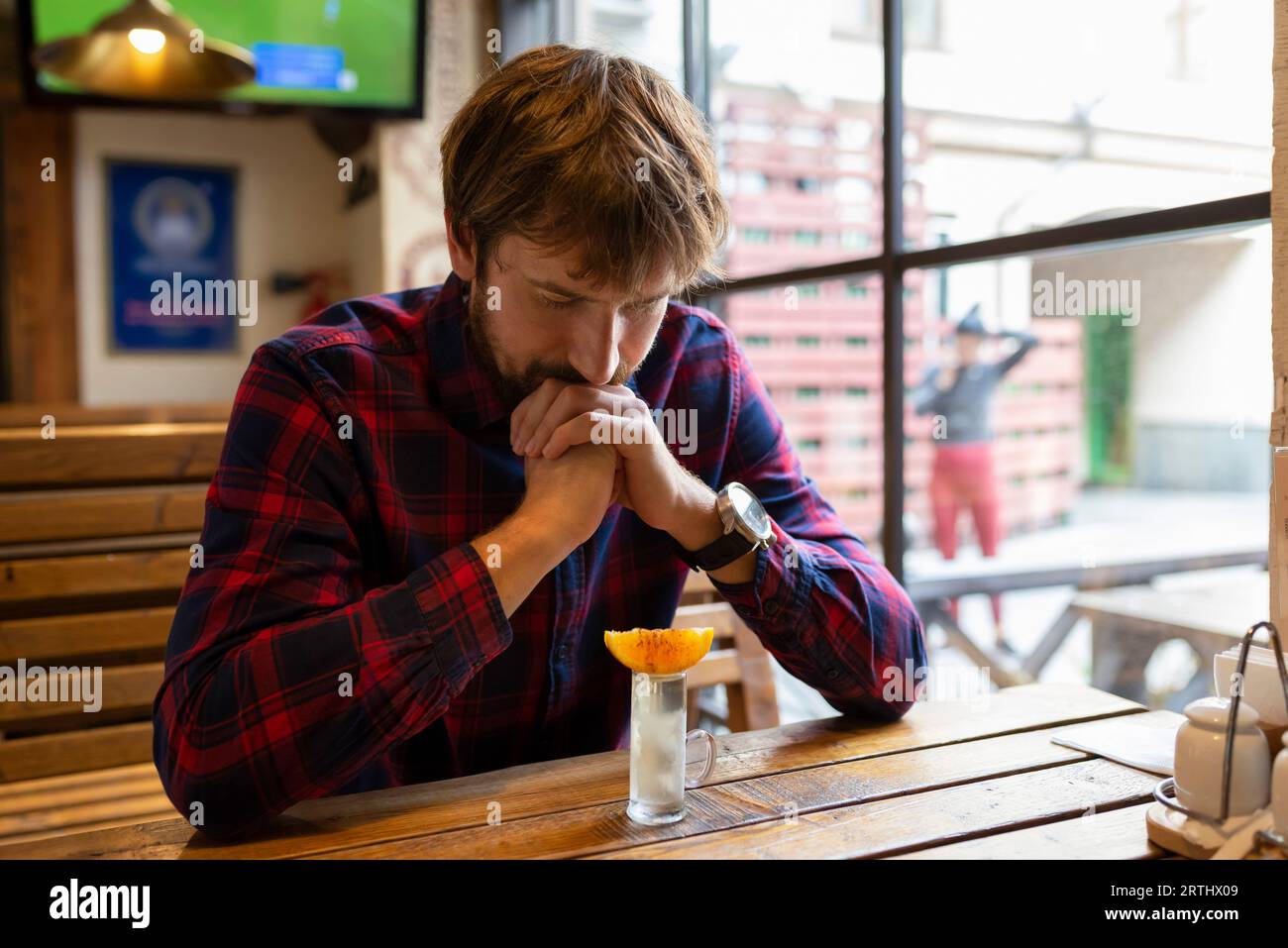 A young man in a bar is struggling with alcohol addiction. The concept ...