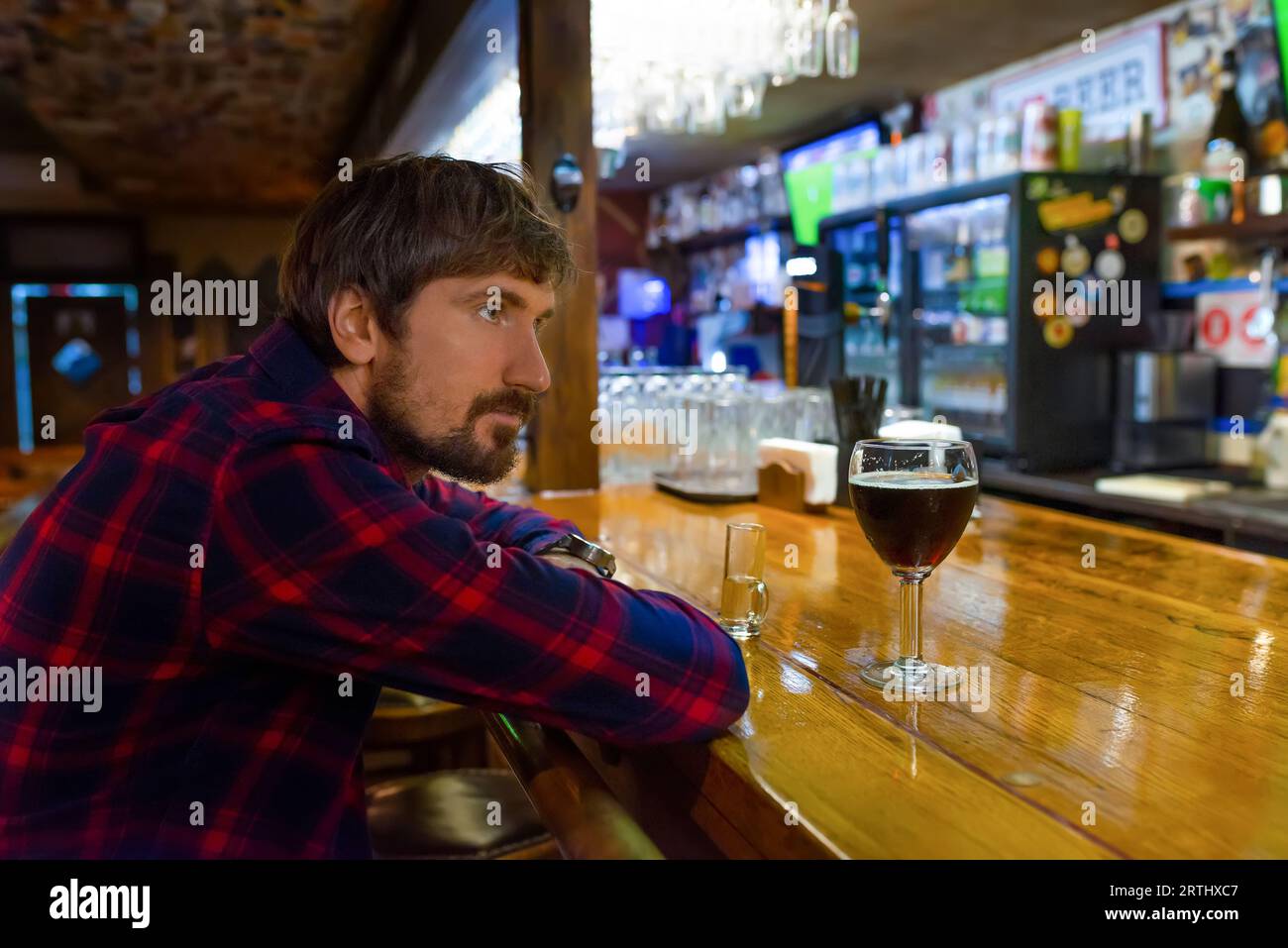A man sits alone at the bar and drinks alcohol. Sad depressed drunk guy ...