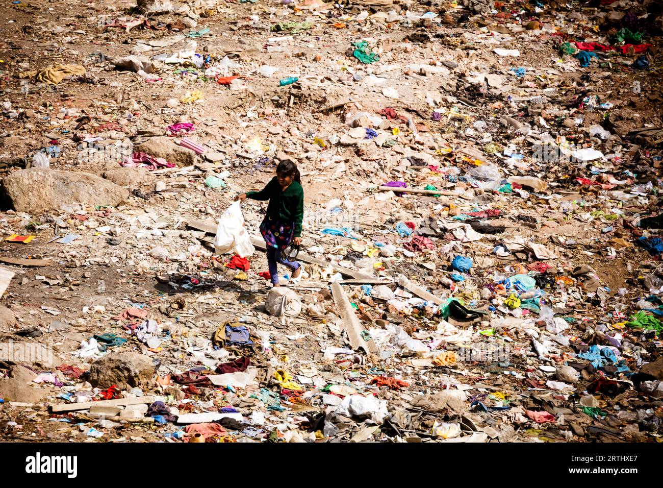 A child plays in piles of trash in a slum in Airoli, Mumbai, INdia ...