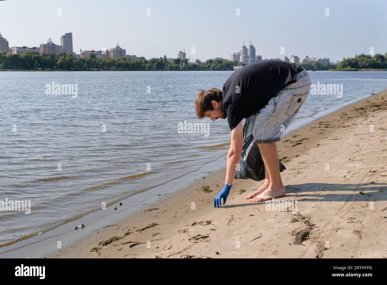 Man collecting plastic waste from a polluted beach using a garbage ...