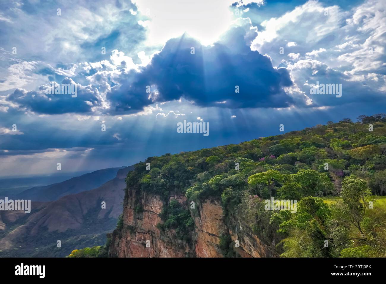Dramatic view of red cliffs covered with rainforest, sunrays falling ...