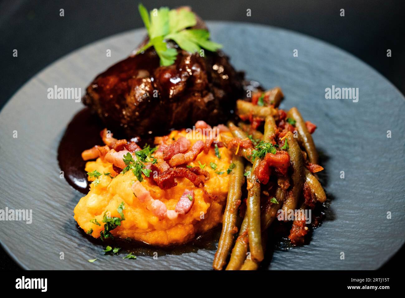 Veal cheeks with sweet potato puree and bacon with beans in tomato ...
