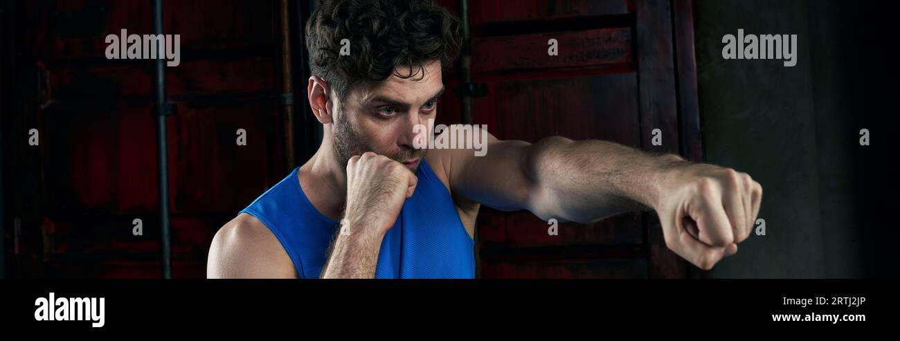 confident unshaven man in blue tank top training and boxing on city ...