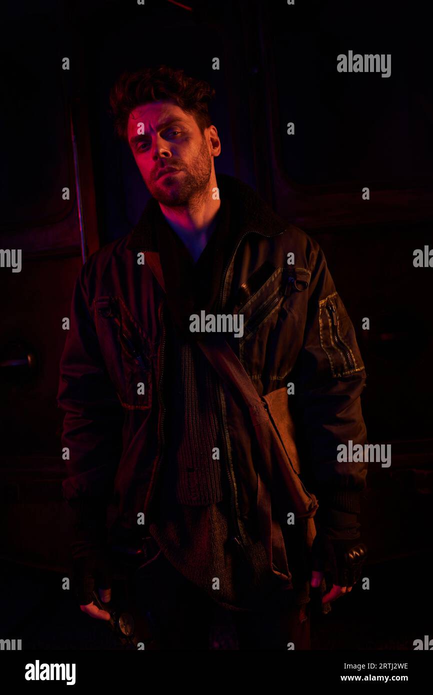 grim man in black worn jacket looking at camera in dark post ...