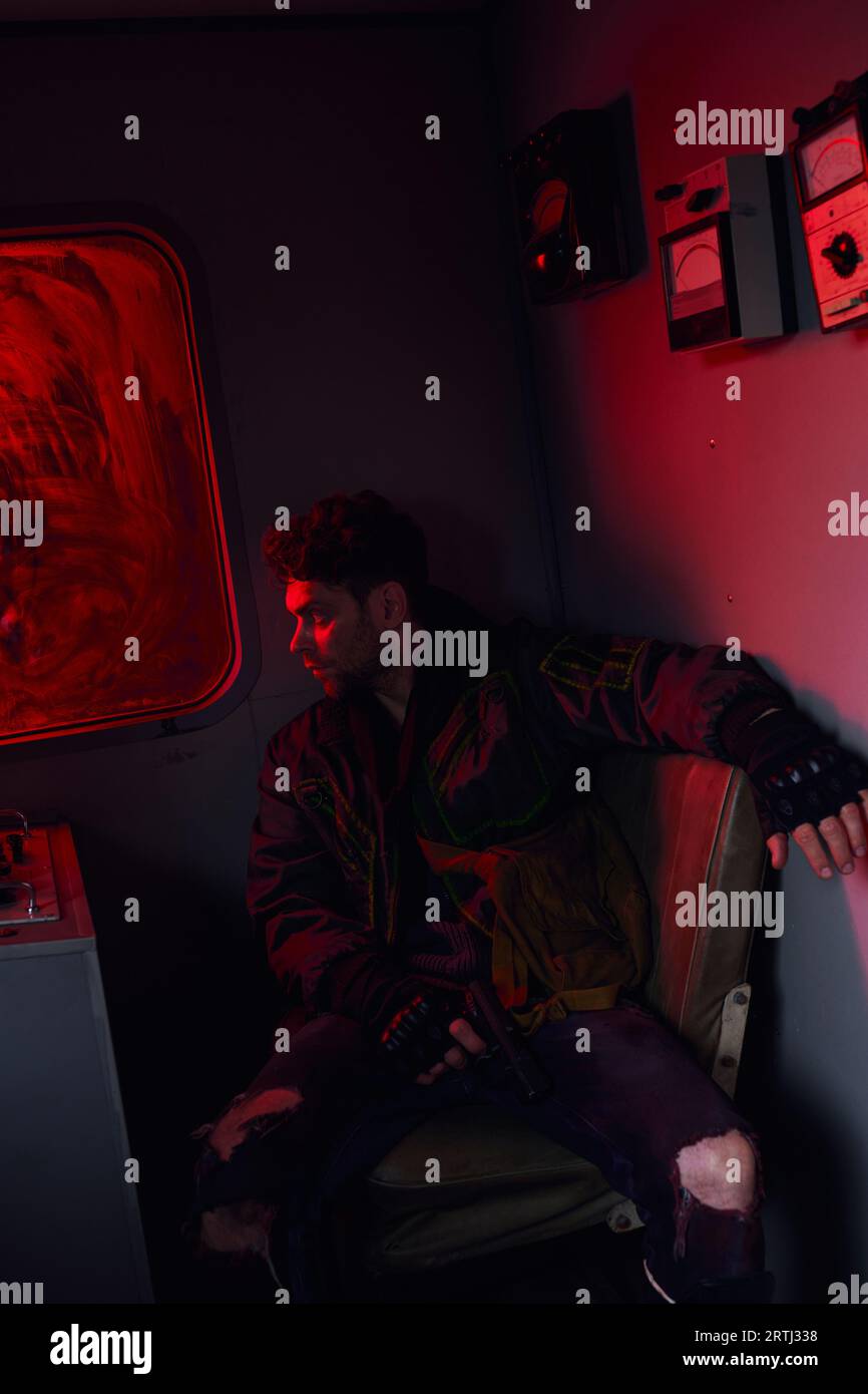despaired man with gun in dirty subway carriage with red light, post ...