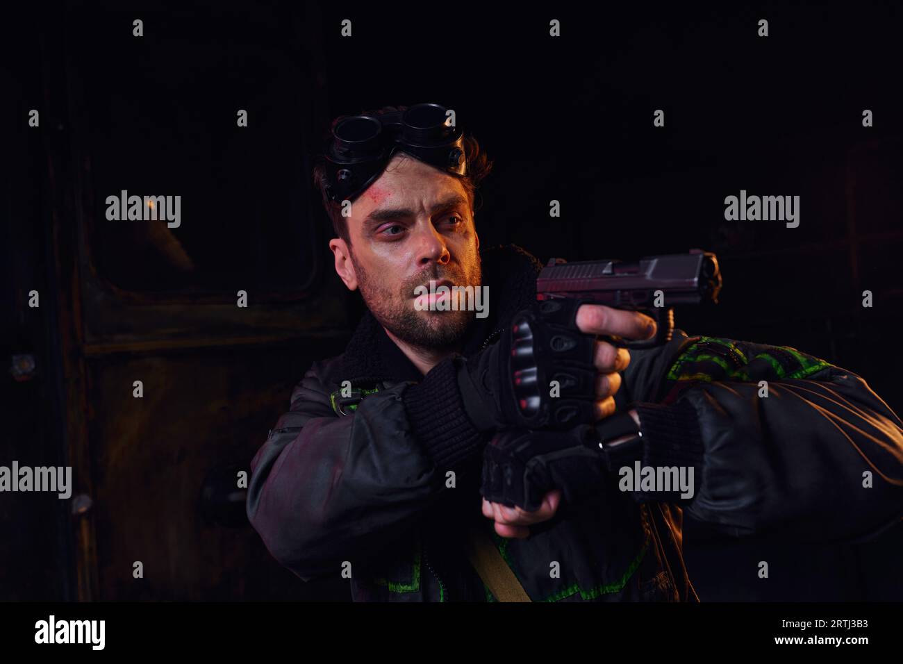 confident unshaven man with military googles aiming with gun in ...