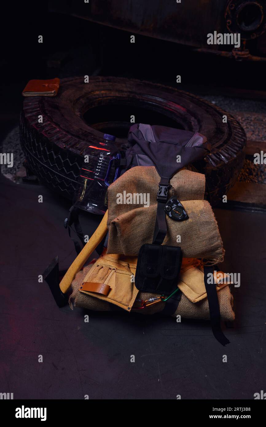 backpack with blanket near tire, axe and water bottle in abandoned ...