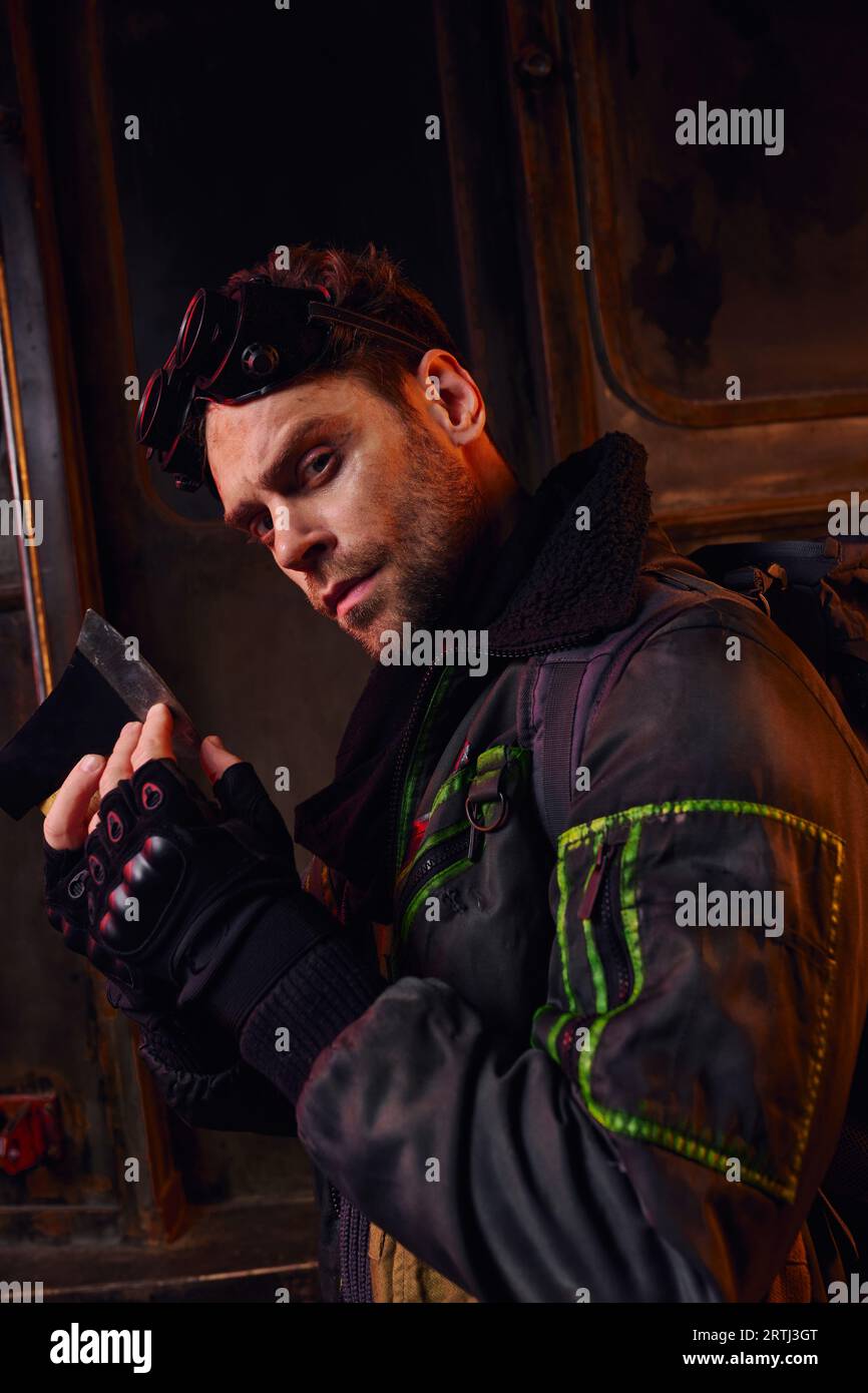 confident man with military goggles and sharp axe looking at camera in ...