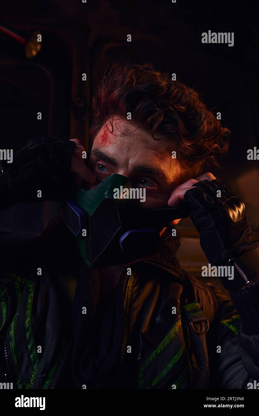 man with scratched face putting on gas mask and looking away in ...