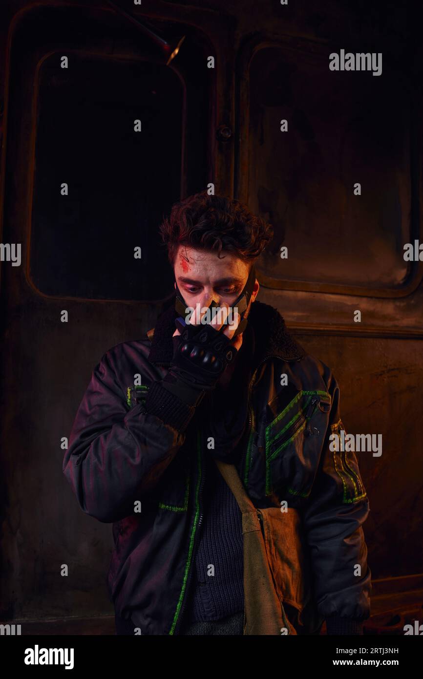 man with scratched face wearing gas mask in toxic environment of subway ...