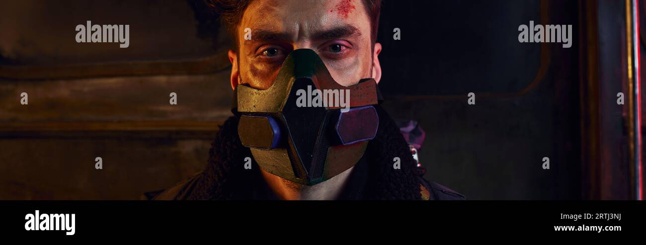 portrait of man with scratched face wearing gas mask in darkness of ...