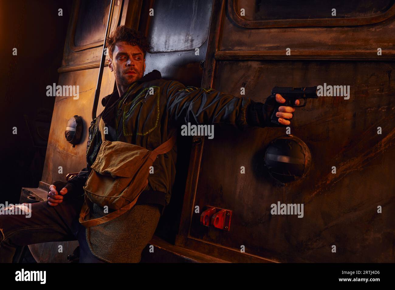 unshaven man hiding behind carriage and aiming with gun in abandoned ...