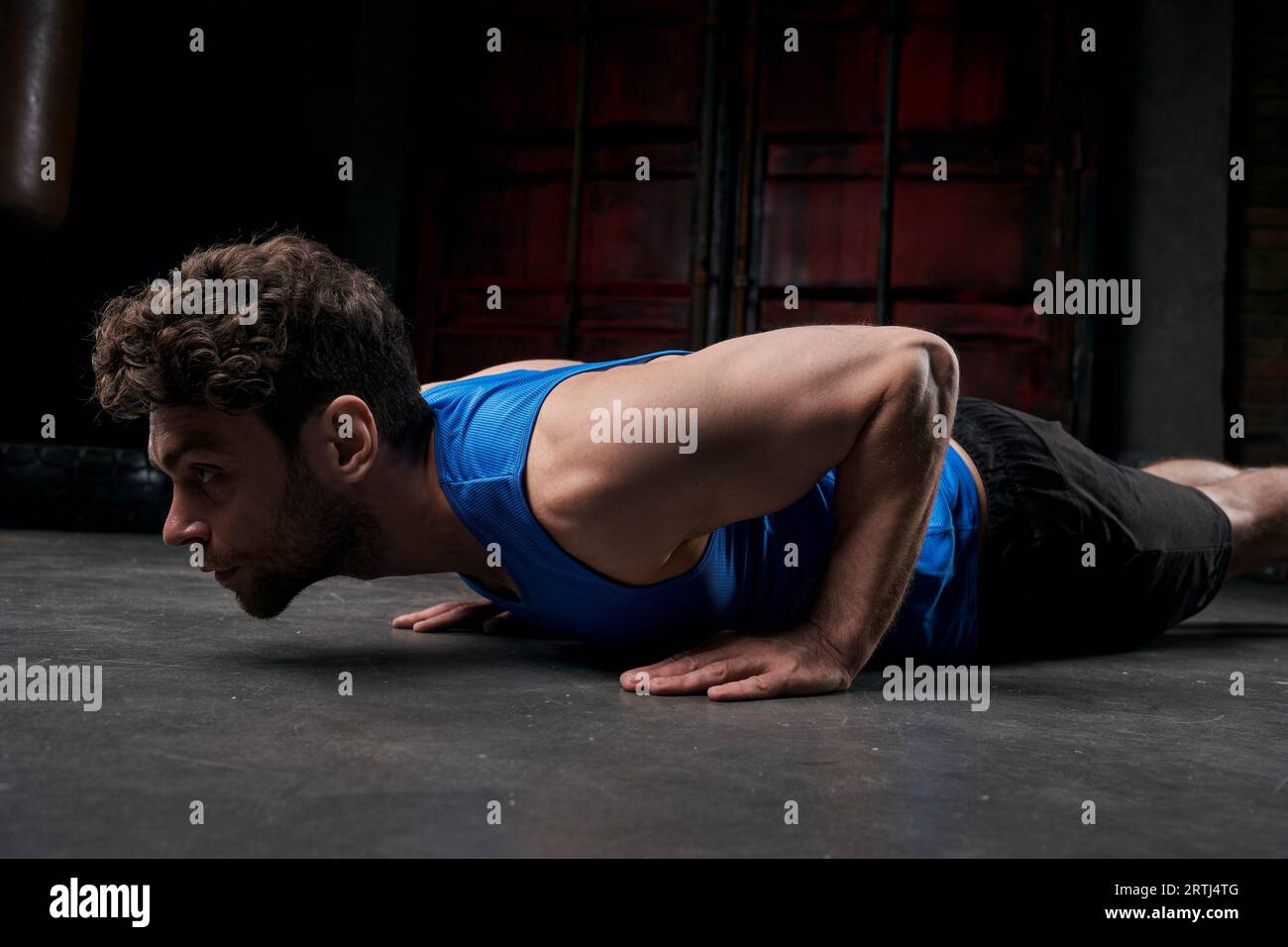 relentless man in blue tank top doing push-ups while working out on ...