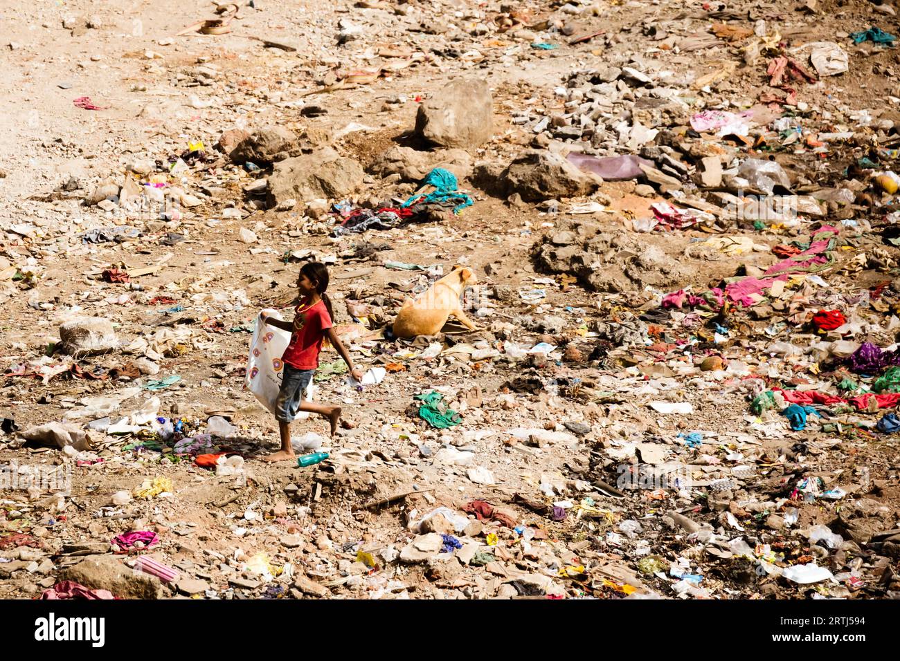 A child plays in piles of trash in a slum in Airoli, Mumbai, INdia ...