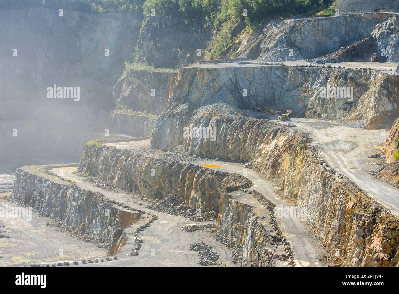 Heavy machines working in dusty porphyry quarry, open-pit mine for the ...