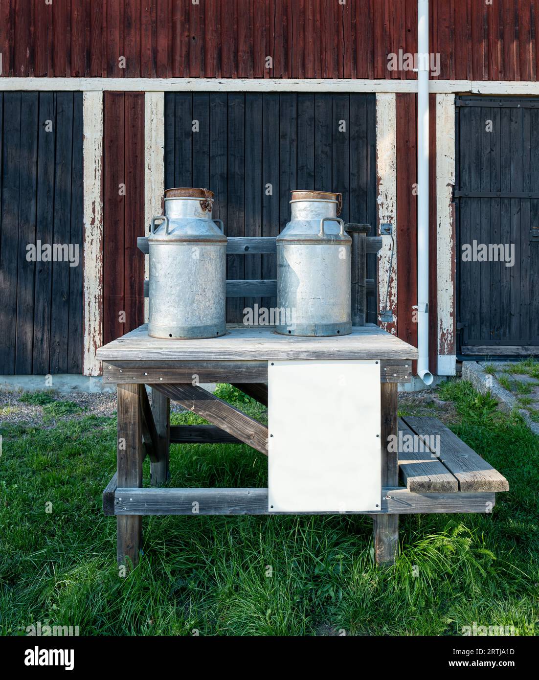 Old milk containers on wooden stand with empty white sign Stock Photo ...