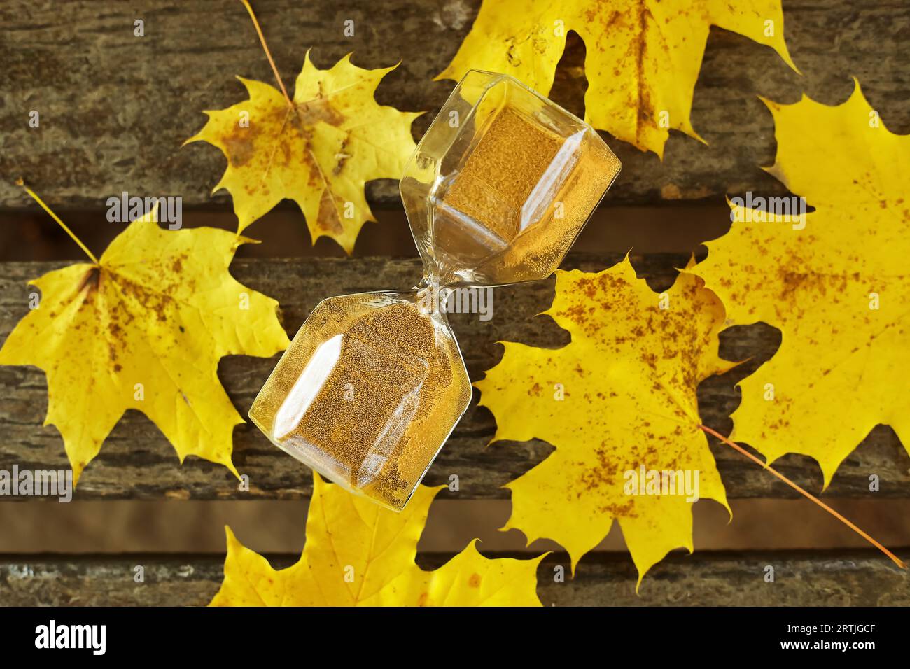 Hourglass with fallen leaves on wooden bench, top view Stock Photo - Alamy