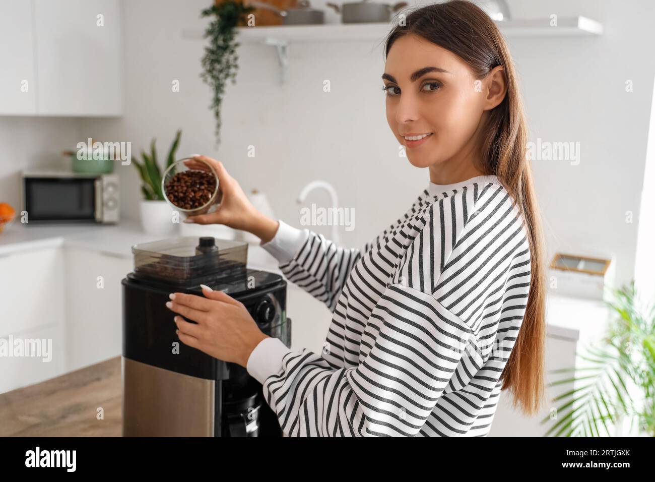 Young woman making coffee in kitchen Stock Photo - Alamy