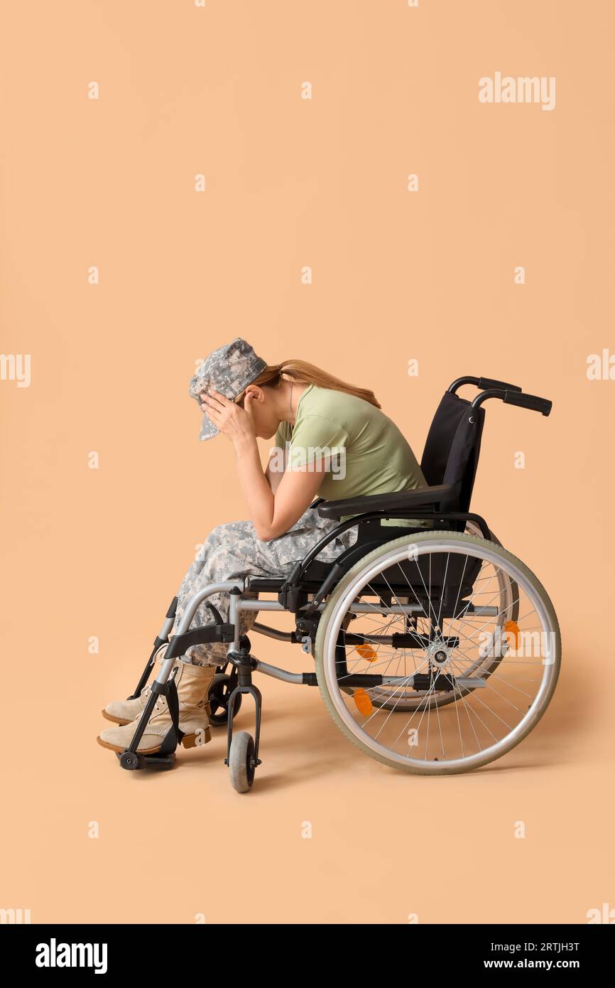 Sad female soldier in wheelchair on beige background Stock Photo - Alamy