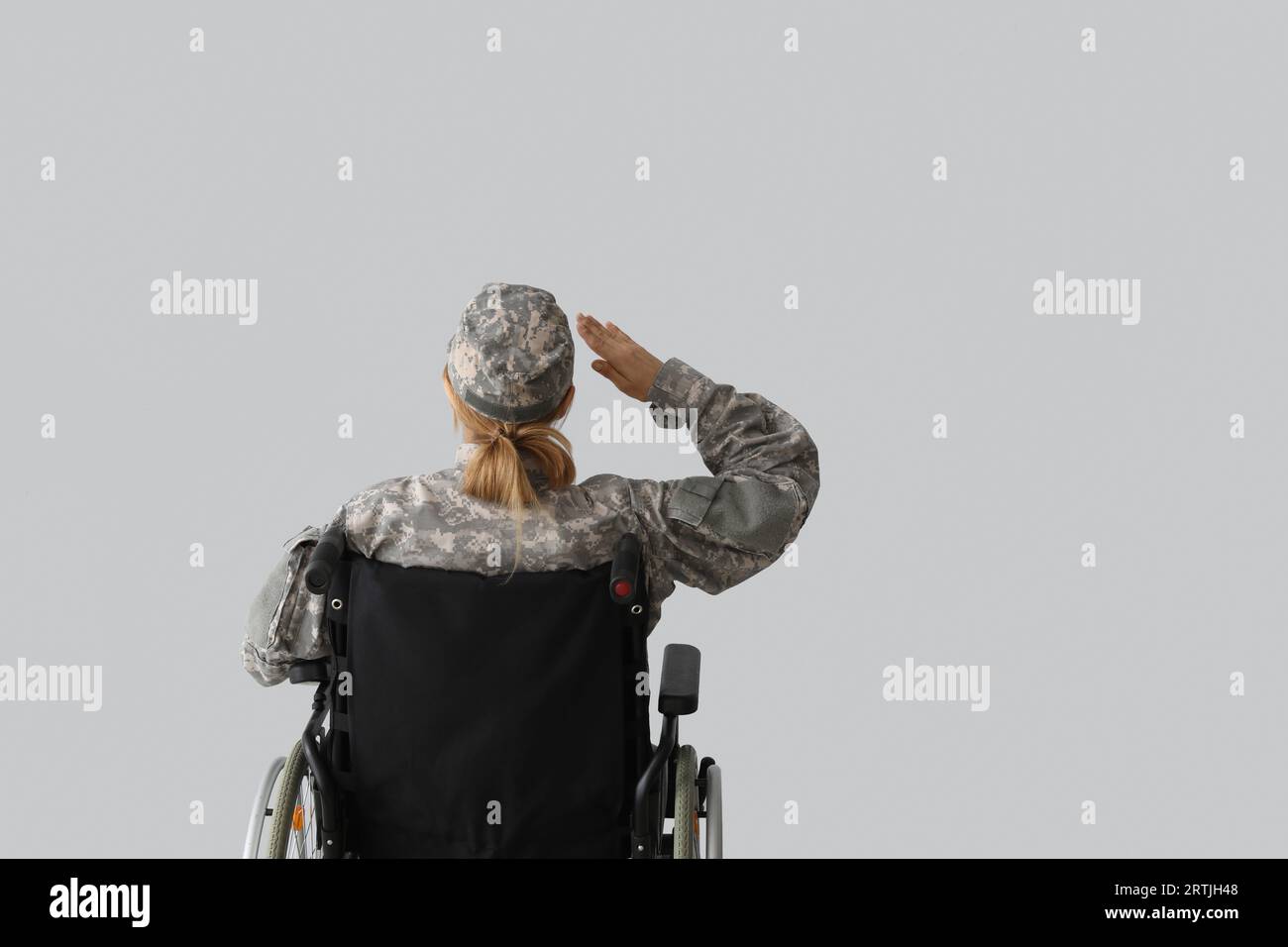 Female soldier in wheelchair saluting on light background, back view ...