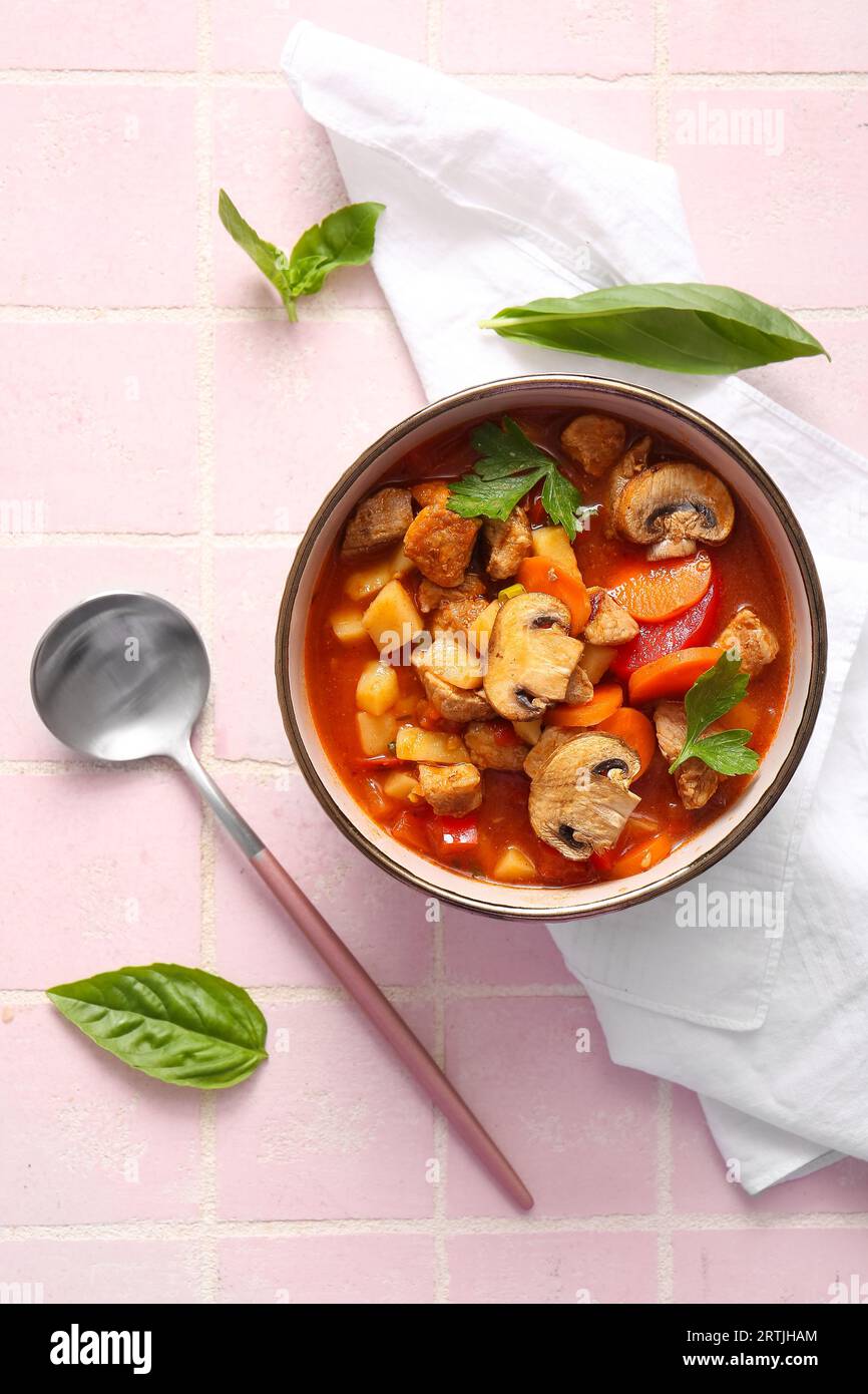 Bowl of tasty beef stew on pink tile background Stock Photo - Alamy