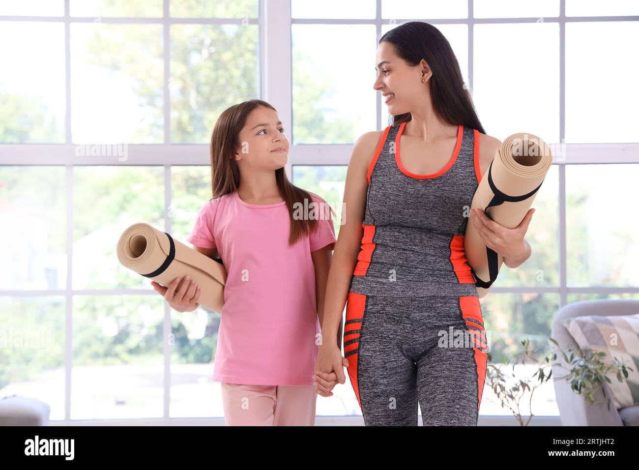 Sporty mother with her little daughter and fitness mats at home Stock ...