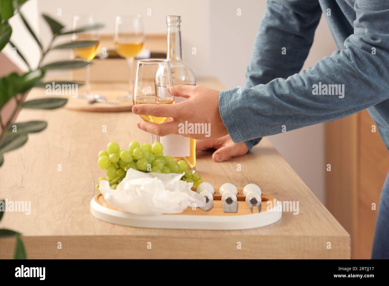 Sommelier with glass of white and grapes at wooden kitchen counter ...