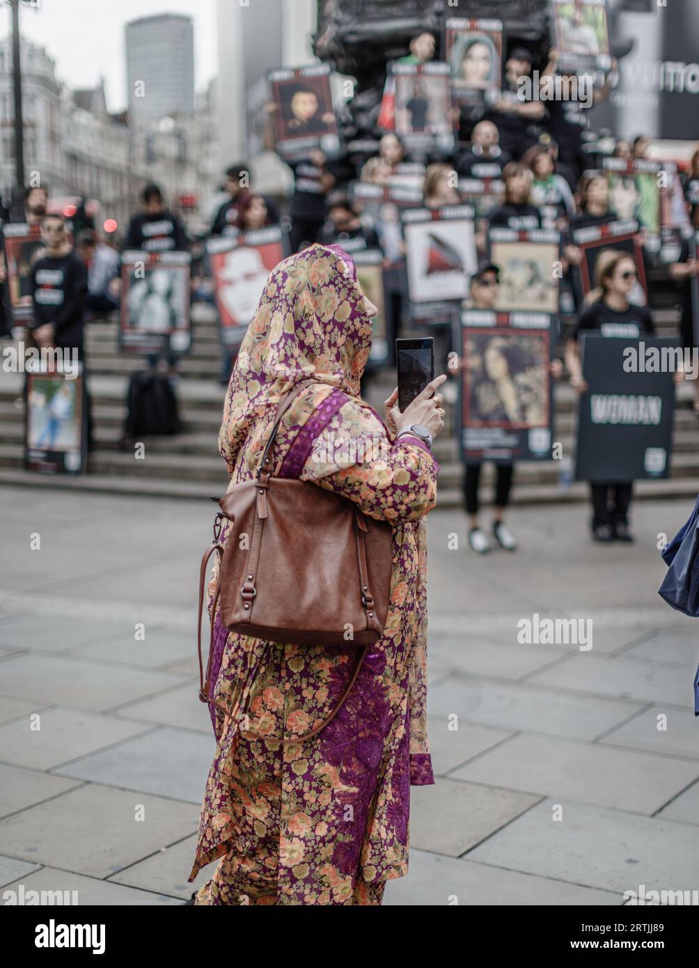 A muslim lady stops to take a photo of protester against the Iranian ...
