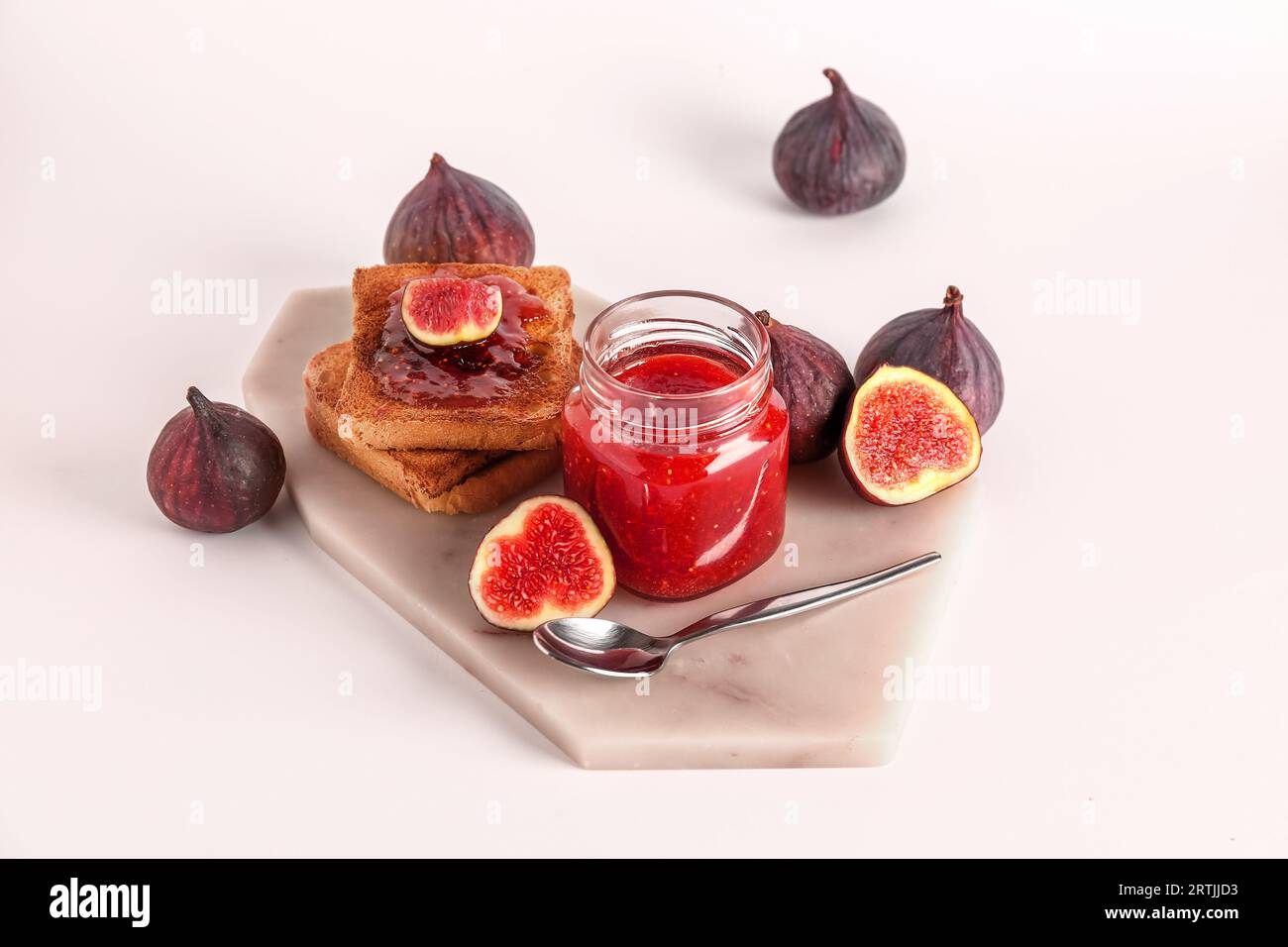 Board with jar of sweet fig jam and tasty toasts on white background ...