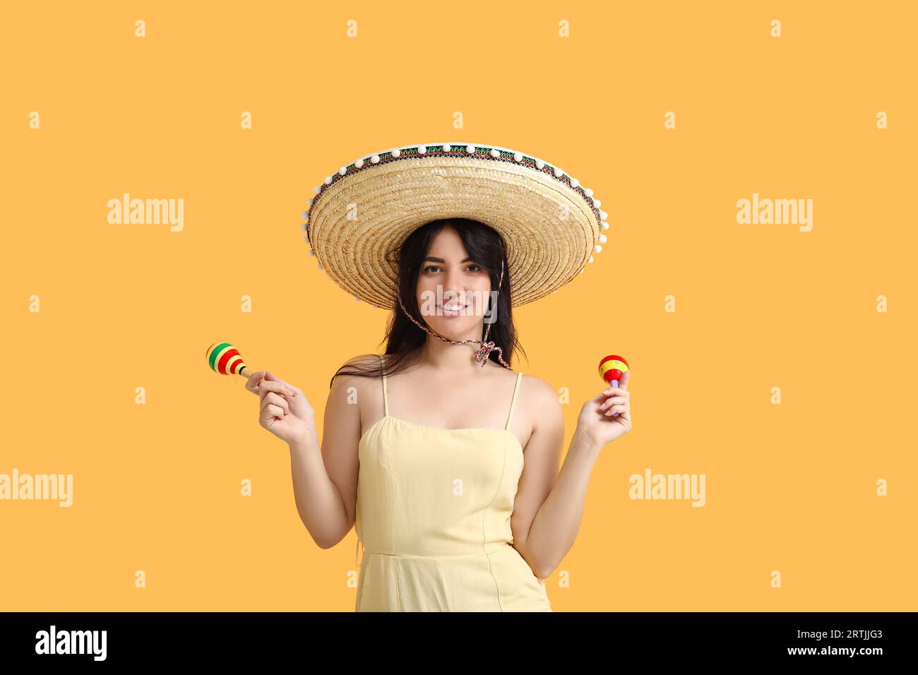 Beautiful Mexican woman in sombrero and with maracas on yellow ...