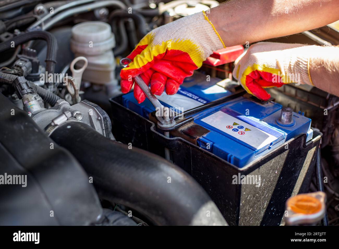 A car mechanic changes a car battery. A man tightens the battery ...