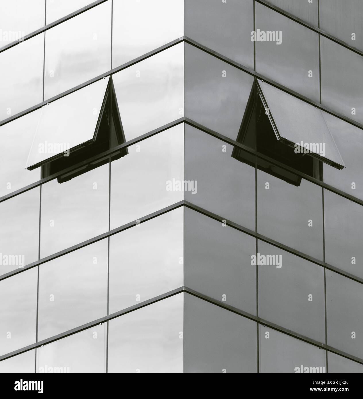 Glass building facade with two open windows. The windows may be ...
