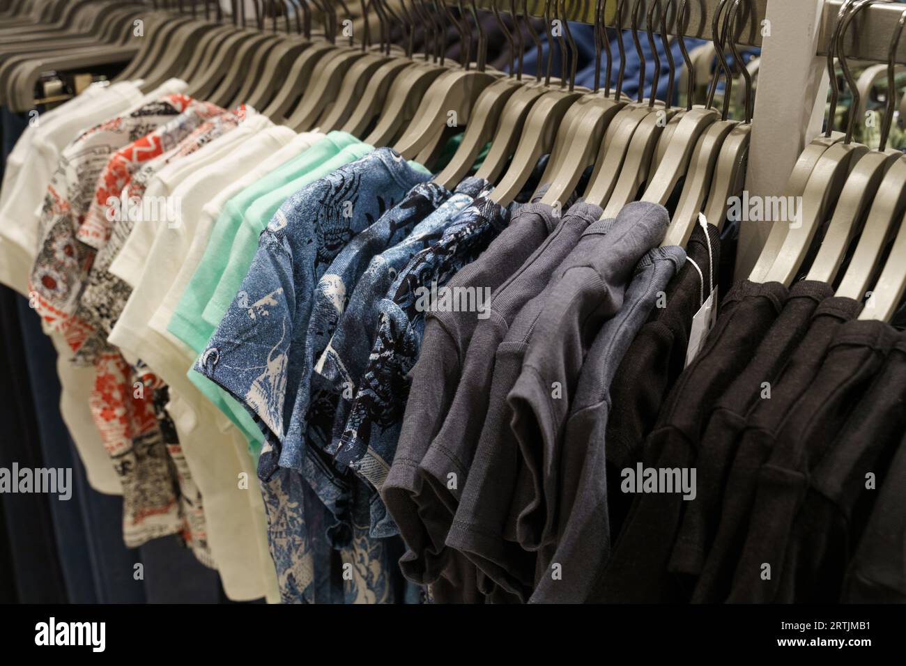 A collection of T-shirts hanging on a clothes rack on a counter in a ...
