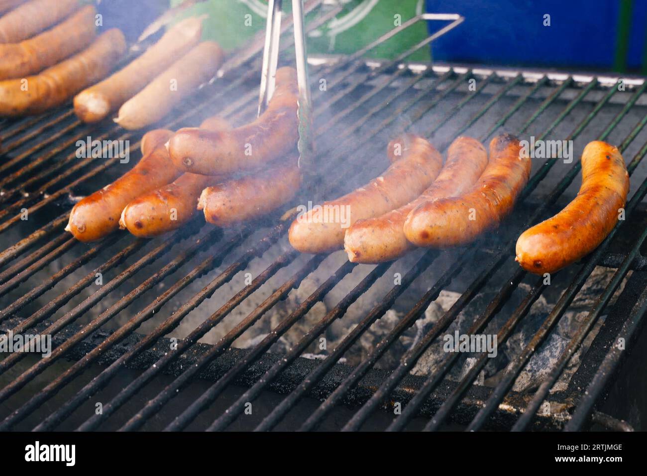 Street food outdoors. The cook prepares grilled sausages on a grill ...