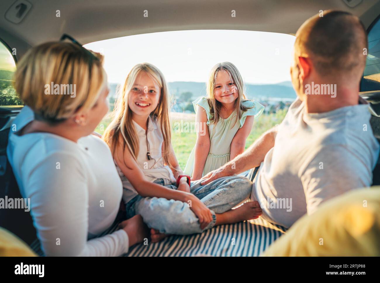 Portrait of happy smiling little sisters. Happy young couple with two daughters inside the car ...