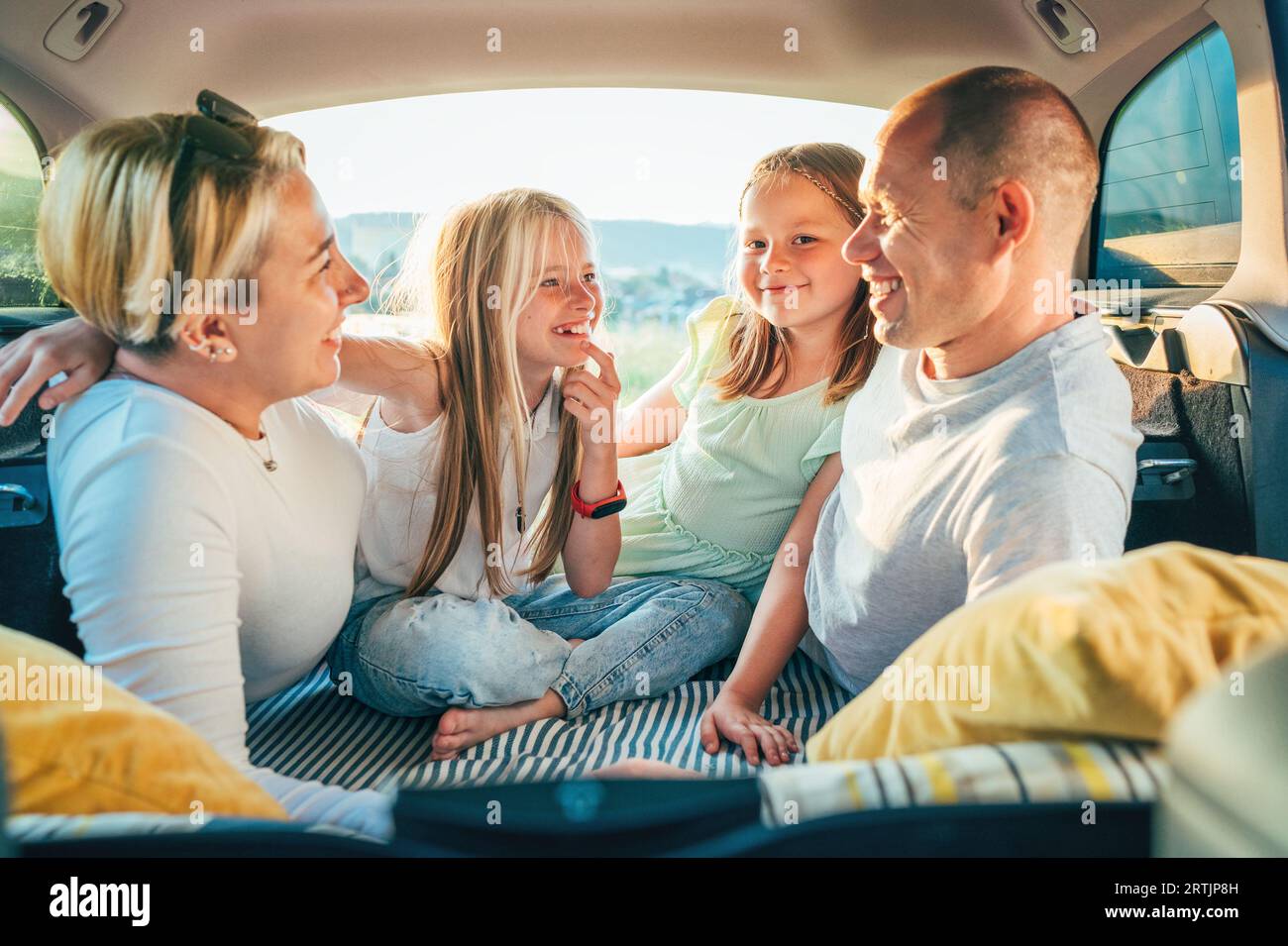 Portrait of happy smiling little sisters. Happy young couple with two daughters inside the car ...