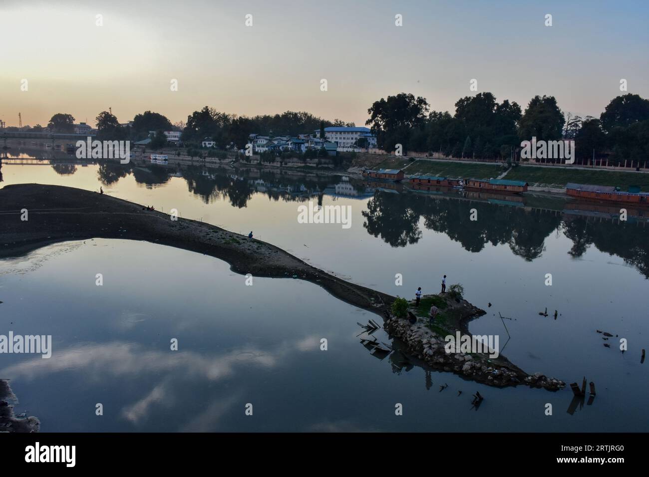 Kashmiri men are seen fishing on the partially dried river Jhelum ...