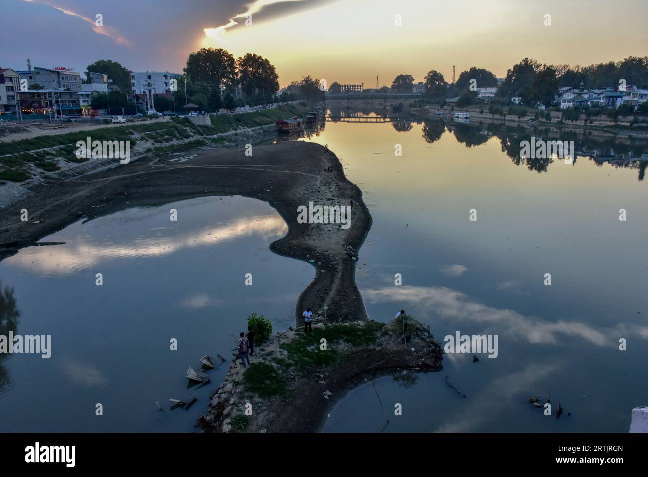 Kashmiri men are seen fishing on the partially dried river Jhelum ...