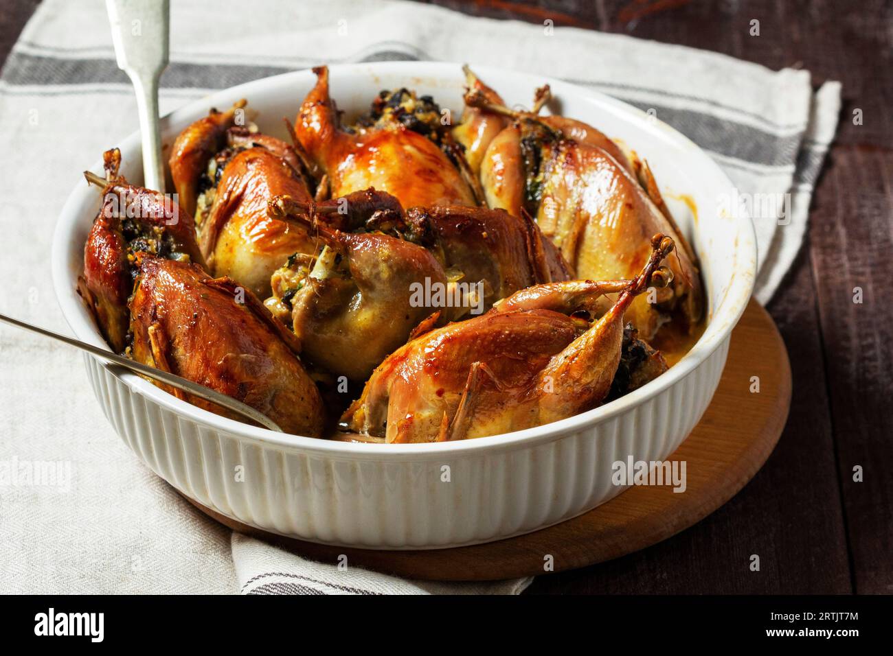 Baked quail stuffed with mushrooms, eggs and bread in a ceramic form on ...
