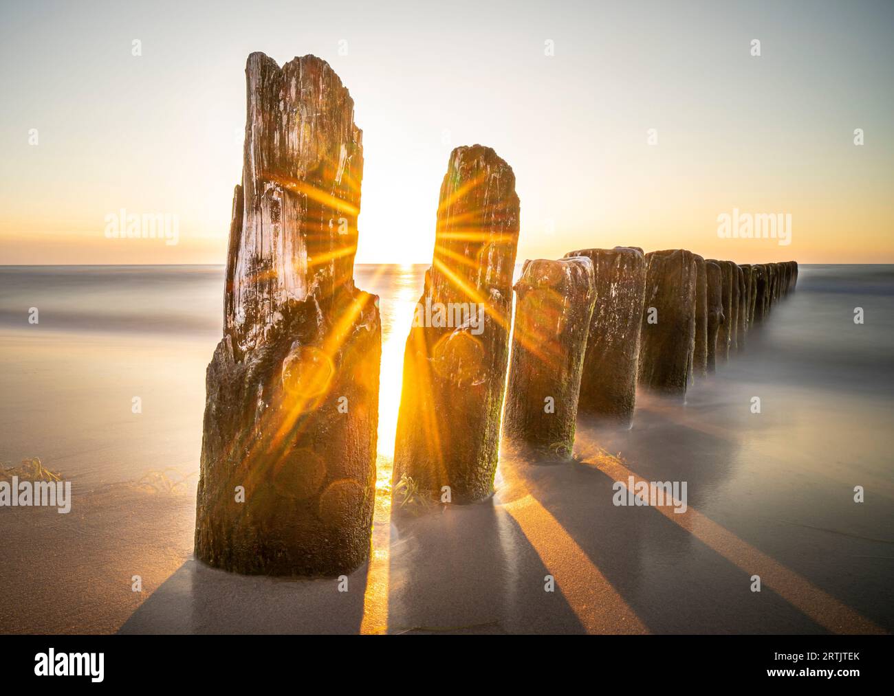 Beautiful sunset over the sea. Sun rays and breakwaters Stock Photo - Alamy