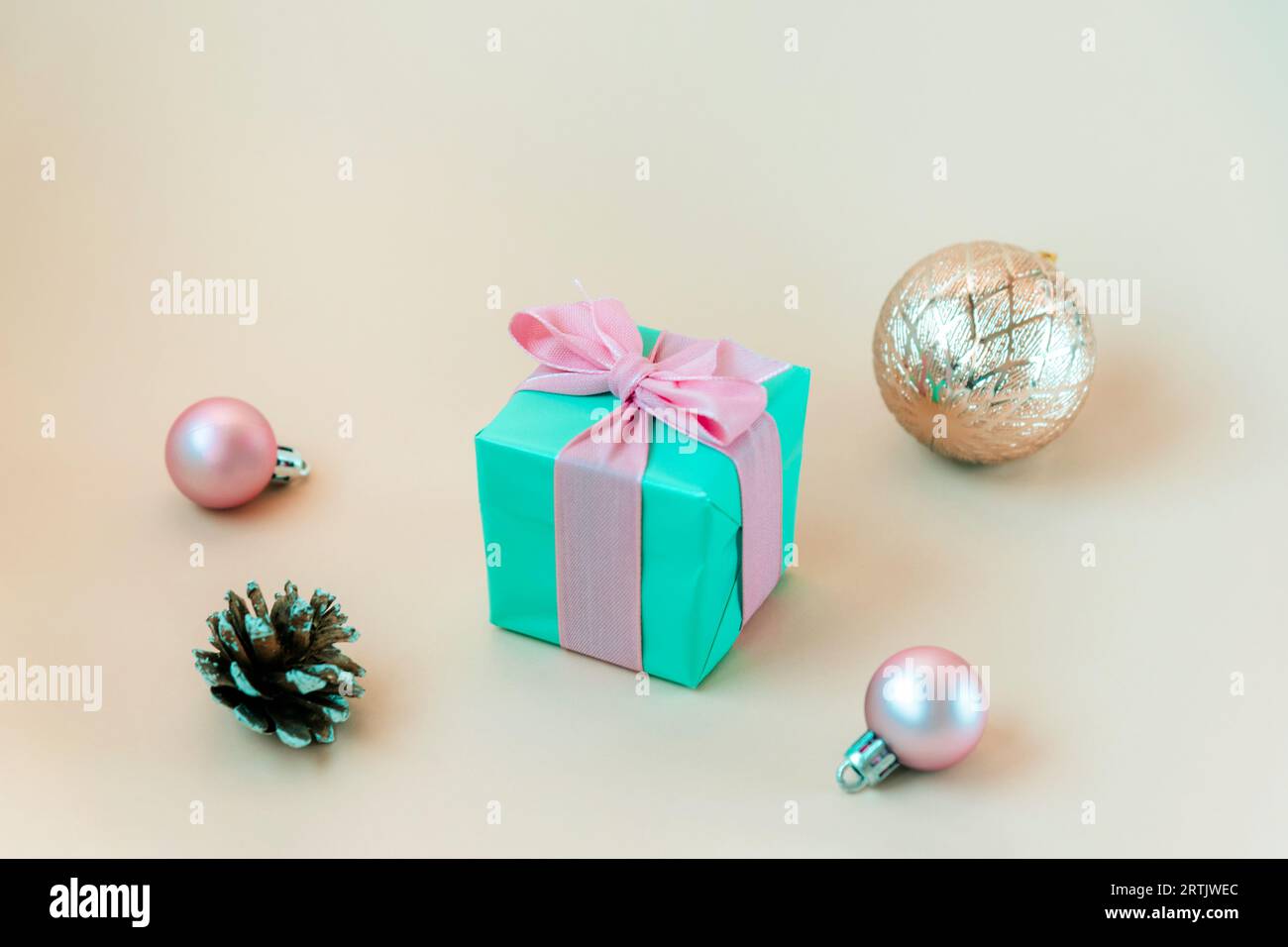 Teal blue gift box with pink bow, Christmas balls and pine cone on ...