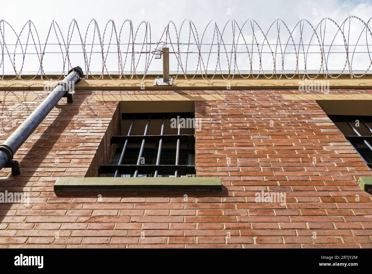 Prison walls with bars on windows surrounded by barbed wire Stock Photo ...