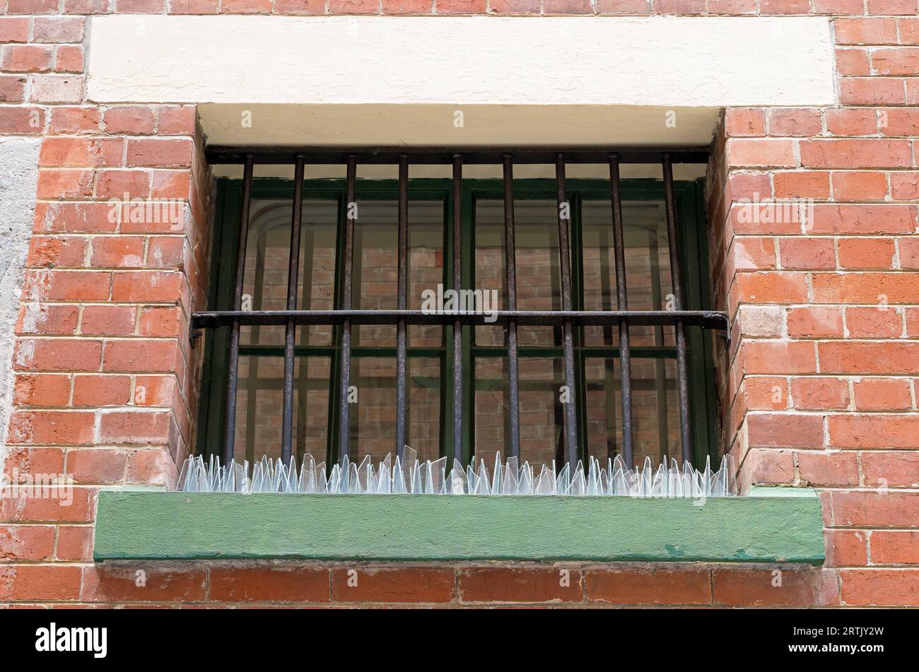 Barred prison window with shards of broken glass at the base of the ...